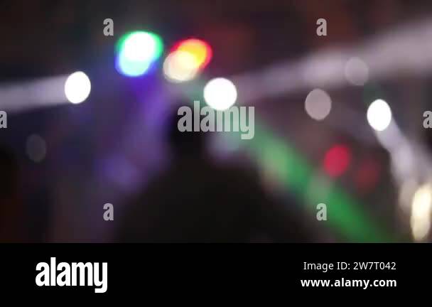 Neon lights on the dance floor. Blurry bokeh. People are jumping on the ...