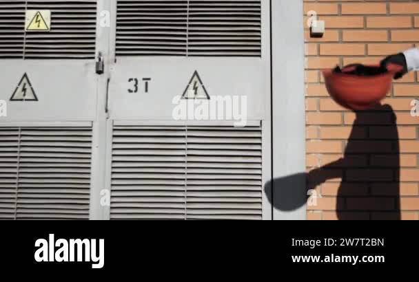 A power engineer shadow puts on a safety helmet on the wall of an ...
