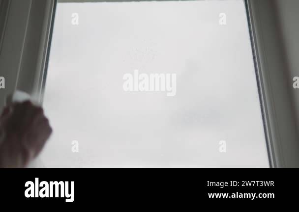 Washing window glass at home. A young long-haired man with a beard is ...