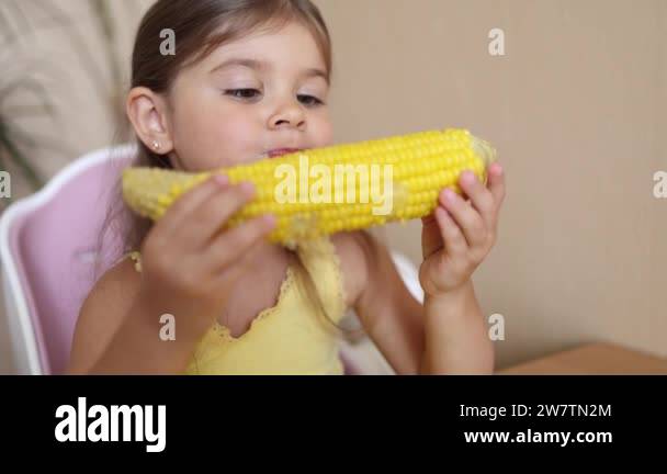 Adorable little girl eating corn at home. Cute kid tree year old eat ...