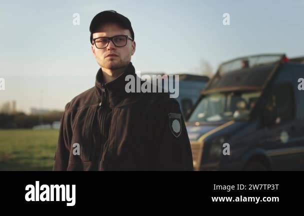 A man in a police uniform is standing and looking around. Hes wearing ...