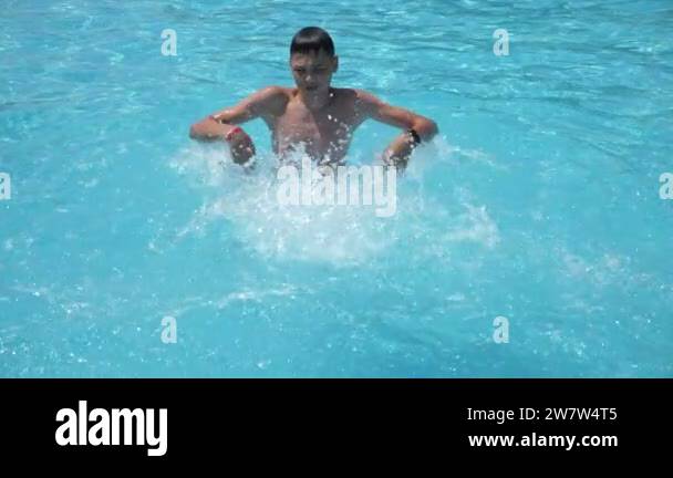 Jolly guy jumping and playing in a wading pool with splattering in slow ...