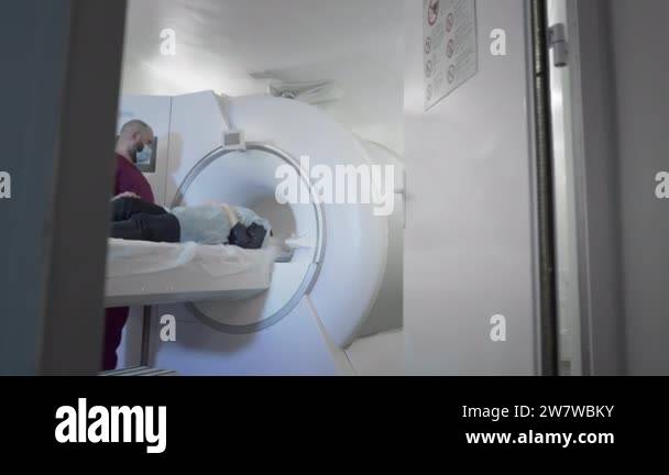 The doctor conducts an MRI or PET scan of a patient in a modern clinic ...