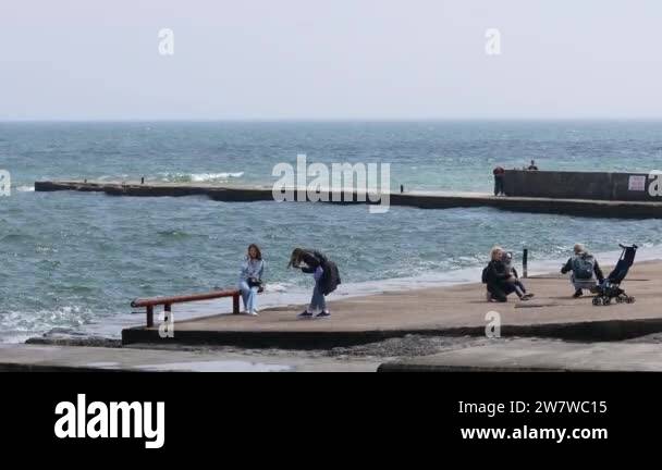 People and families walk along the seashore on a spring sunny day ...