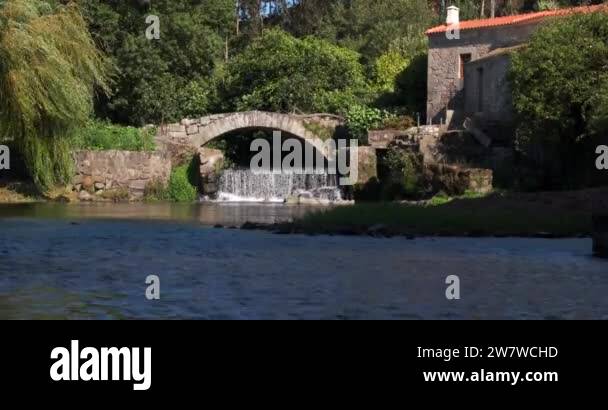 Beautiful waterfall flowing under old medieval bridge in rural Portugal ...