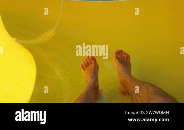 enjoying on waterslide during summer vacation, feet of man slides down ...