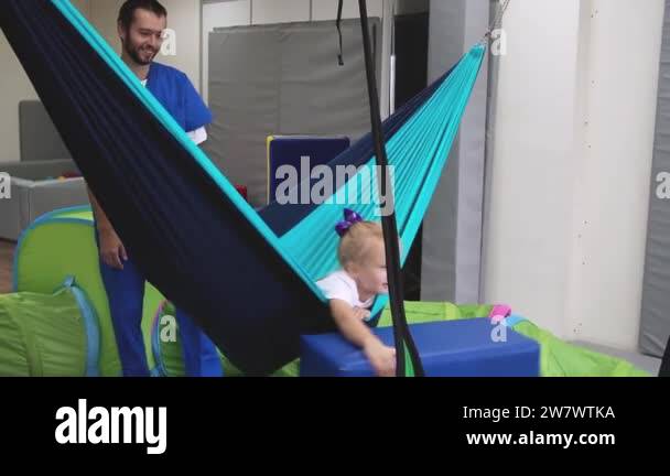 Child girl with physiotherapist swinging on swing during sensory ...