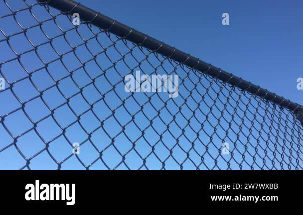 Low angle view of cyclone chain wire mesh fencing against blue sky ...