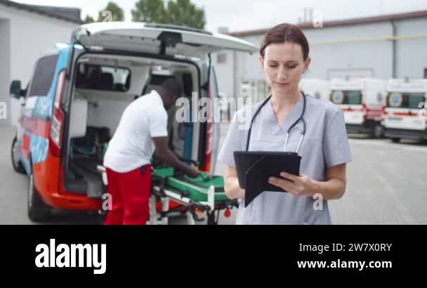 Female doctor filling in medical form and using table device. Outdoor ...