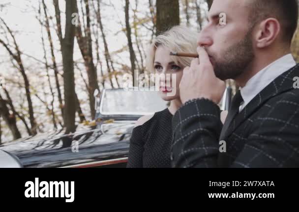 Glamorous couple, man smoking cigar and they looking straight at retro ...