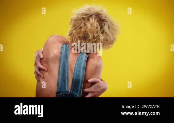 Back view of young Caucasian LGBT man hugging himself turning to camera ...