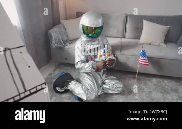 Afro american man in an astronaut costume sitting on the floor in ...