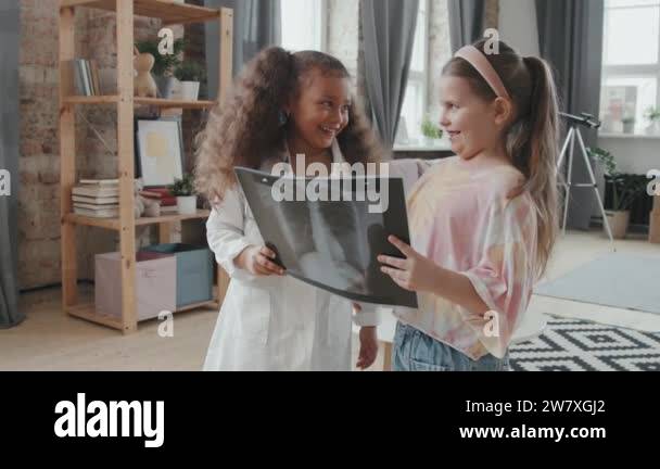 Handheld tracking with slowmo of cheerful 8-year-old girl in white coat ...