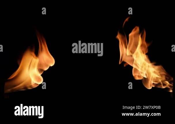 Two flames of fire blaze from different sides of screen in dark. Real ...