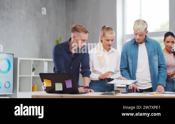 Team of young startupers is working at the table in the office, discussing the strategy and ...