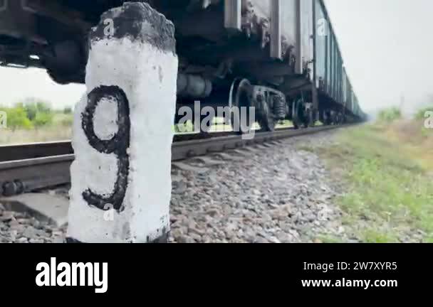 Concrete mark on railroad, freight train carriages pass along rails ...