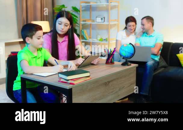 In the large living room sister and brother doing a school project ...