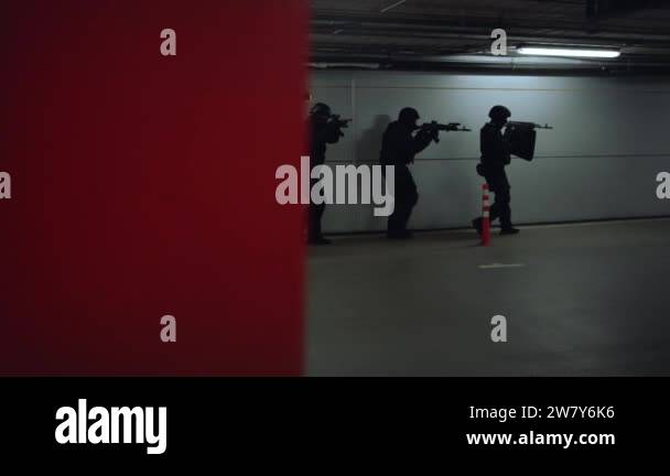 SWAT police officers walking on parking. Special forces aiming assault ...