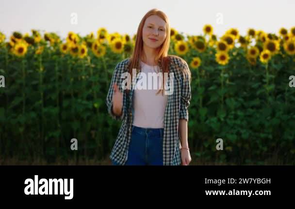 A young foxy looking woman is wearing a checkered blouse and standing ...