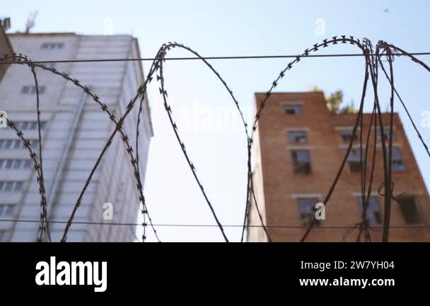 High concrete fence with barbed wire against blue sky background ...