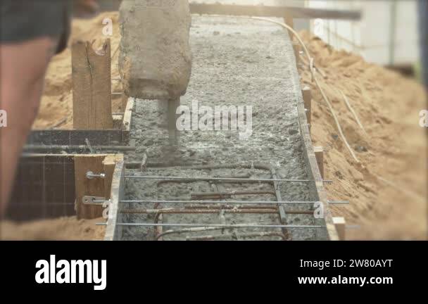 Pouring ready-mixed concrete in formwork with reinforcement. Wet cement ...