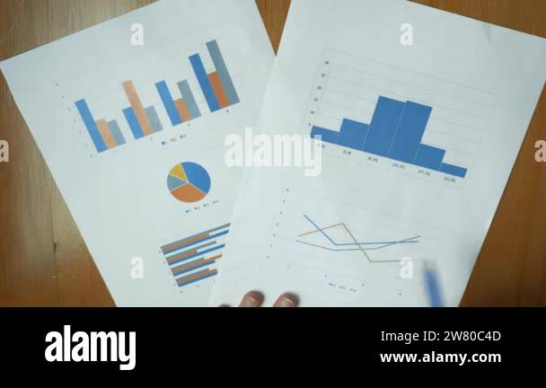 Top down view of papers with different colorful line graphs, bar graphs and pie charts being ...