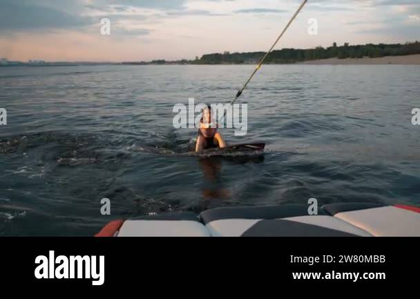A female surfer jumping on a wakeboard. An experienced wakeboarder ...