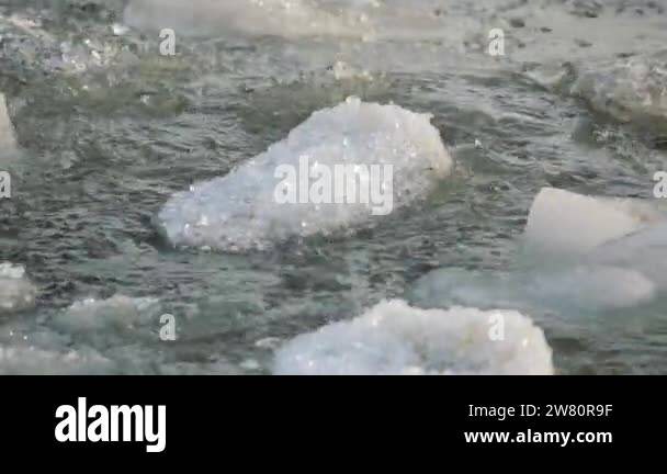 A beautiful piece of ice similar to a crystal swings on the water and ...