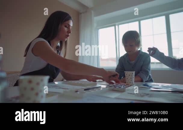 Group of kids and their teacher leaning over table with watercolor ...