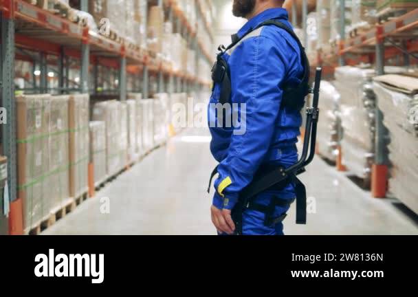 Warehouse with a male specialist wearing exoskeleton. Exoskeleton ...
