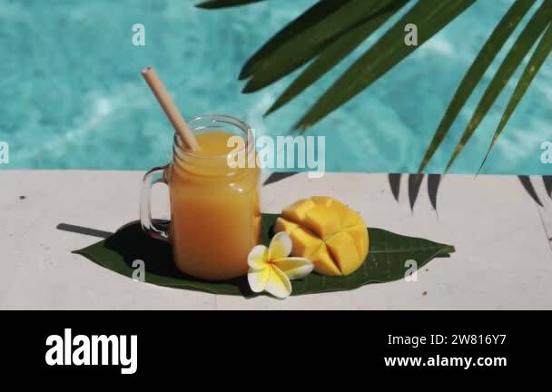Video footage of glass mason jar with mango juice, bamboo straw, half ...