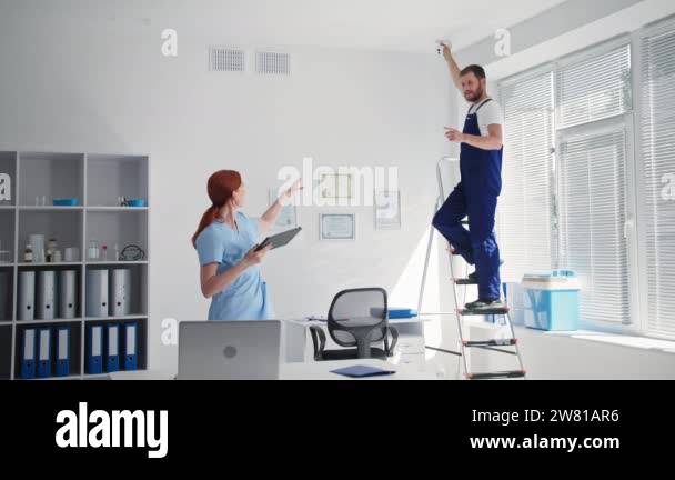 installation of surveillance camera in an office, young female doctor ...