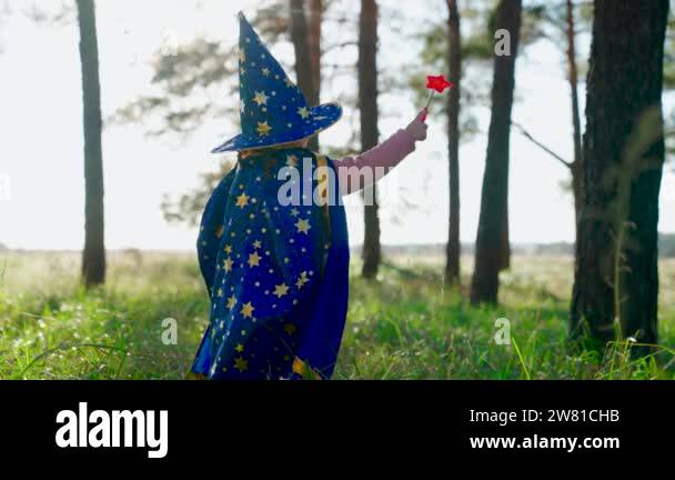 Child fantasizes in mantle of magician in forest. A girl, child plays ...