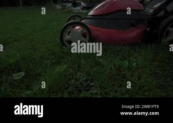 Man cut grass with lawn mower in house yard near swing in playground ...