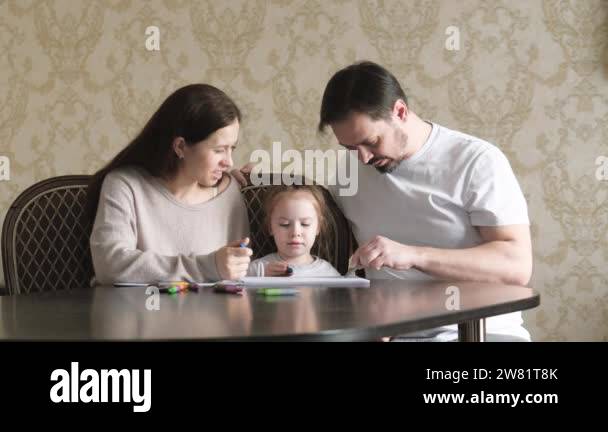 Family education. A little girl, with her parents, draws with colored ...