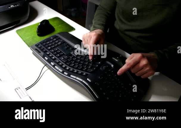 European man slow typing with two finger system on ergonomic keyboard ...