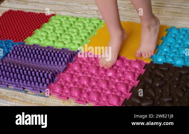 A child jumps on an orthopedic massage mat made of puzzles with ...