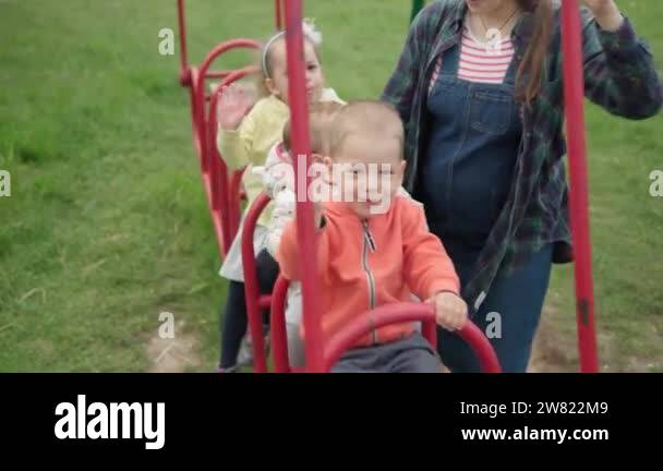Cute pretty Preschool children with young mom frolic in swing train on ...