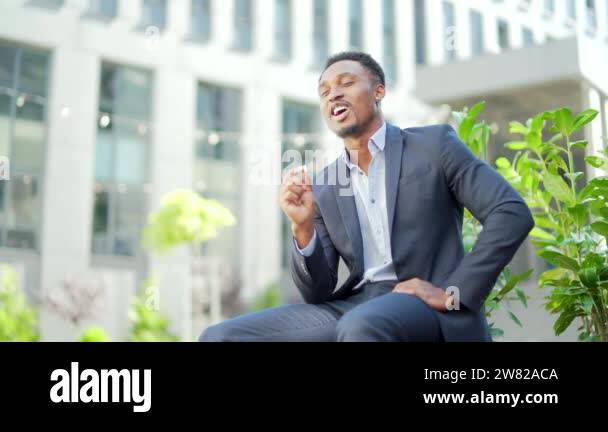 african american business man smoking cannabis outdoors sitting on city ...