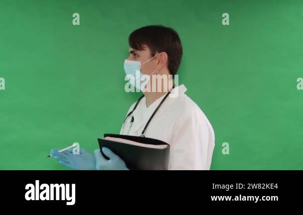 A doctor in a white coat with a folder in his hands turns in different ...