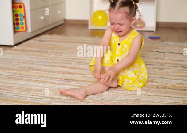 A little two-year-old girl has hit her big toe and is crying in pain ...