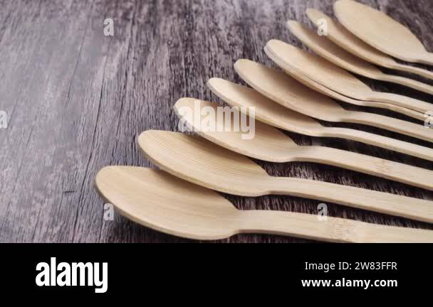 Wooden bamboo spoons on a rustic wood surface. Disposable picnic set. Kitchen ecological ...