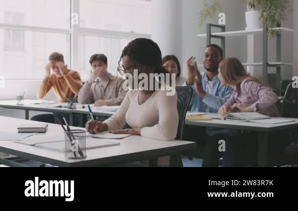 Victim of bullying. African american girl sitting alone in classroom ...