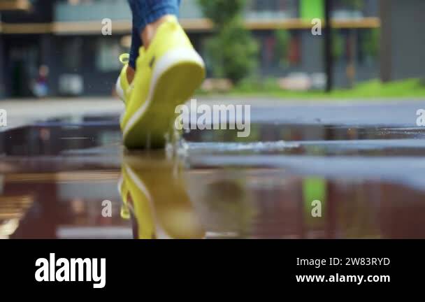 Female sports woman jogging outdoors, stepping into puddle. Single ...