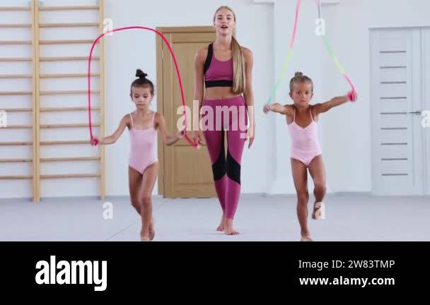 Two little girls gymnasts walking forwards while jumping over the rope ...