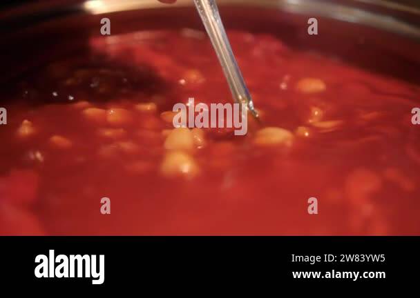 Spoon stirring delicious traditional Mexican pozole in cooking pot ...