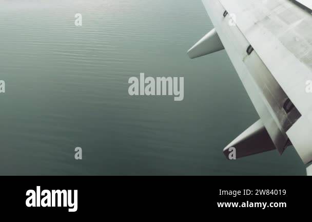 Commercial flight landing above water, looking to the left of the frame ...