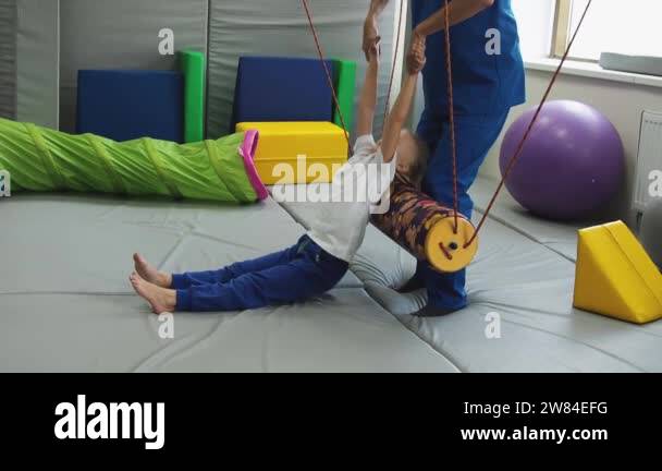 Child girl with physiotherapist swinging on swing during sensory ...