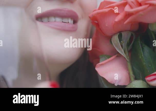 A close-up of a girls smile holding a bouquet of red roses and a ...