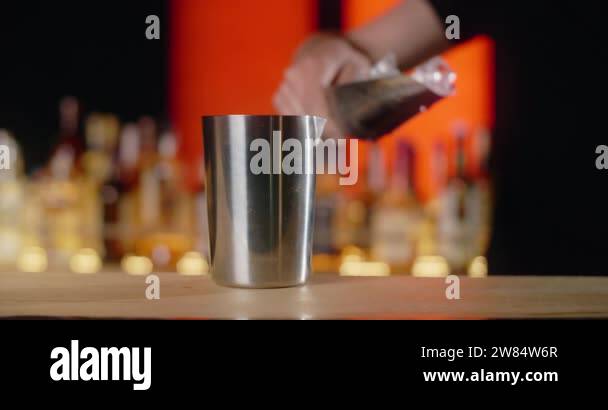 Barman adds ice cubes to the shaker in slow motion, bartender mixes cocktails on the bar counter ...